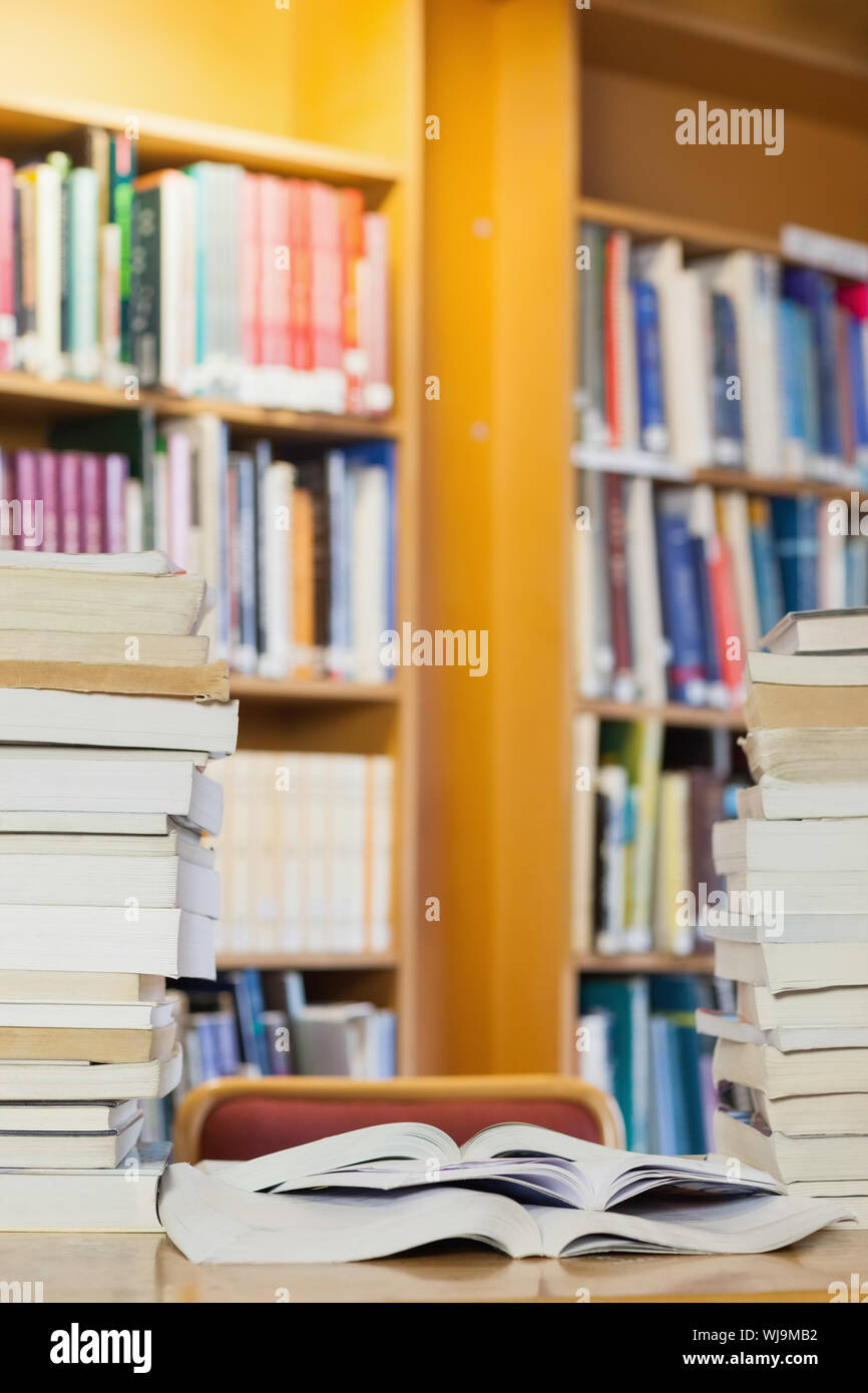 Piles of books on desk in library Stock Photo - Alamy