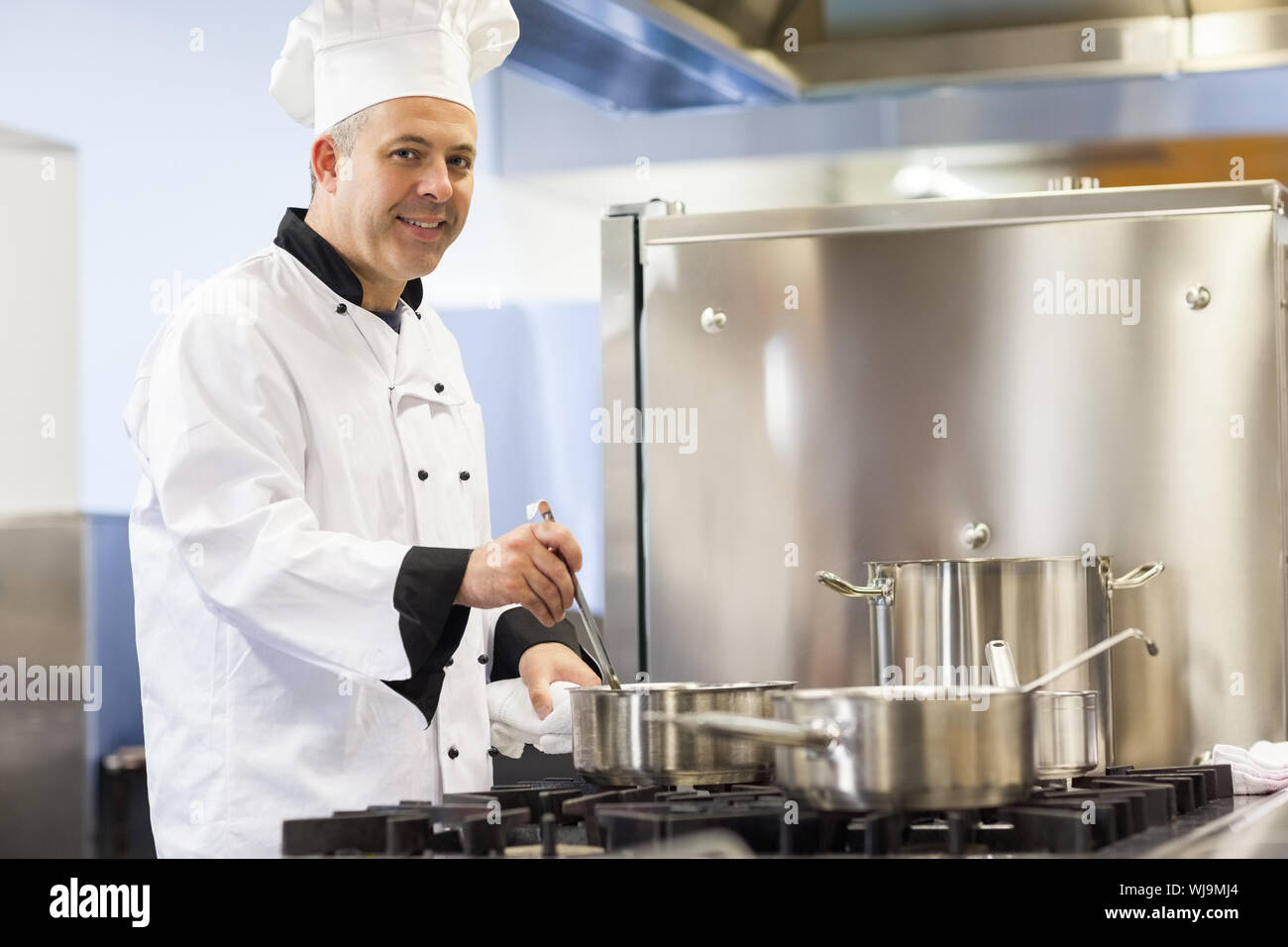 Smiling head chef stirring in pot in professional kitchen Stock Photo ...