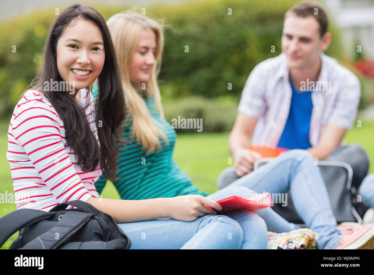 Group of three young college students sitting in the park Stock Photo ...