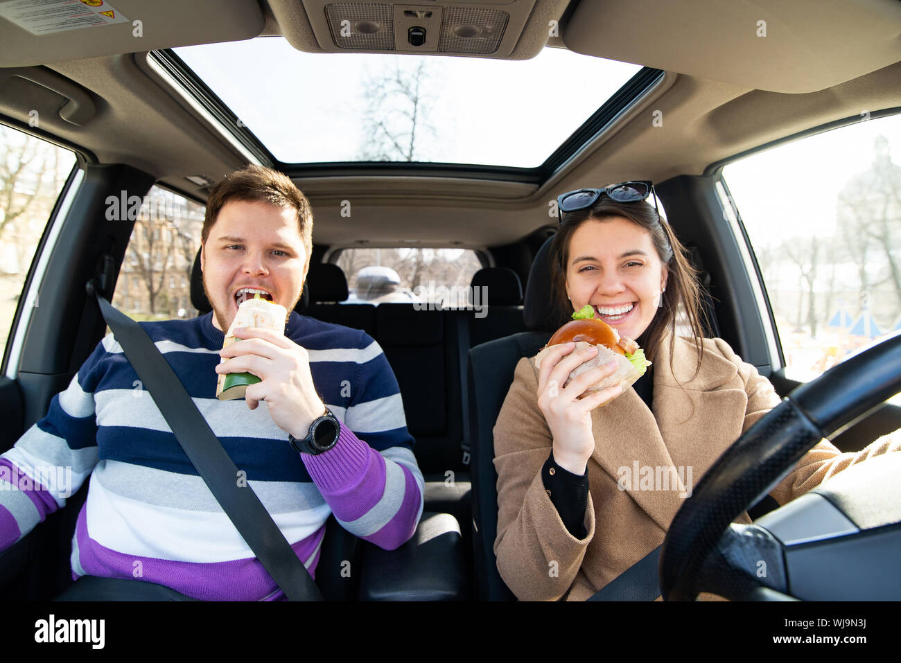 young couple eating fast food in car. modern rhythm lifestyle Stock ...
