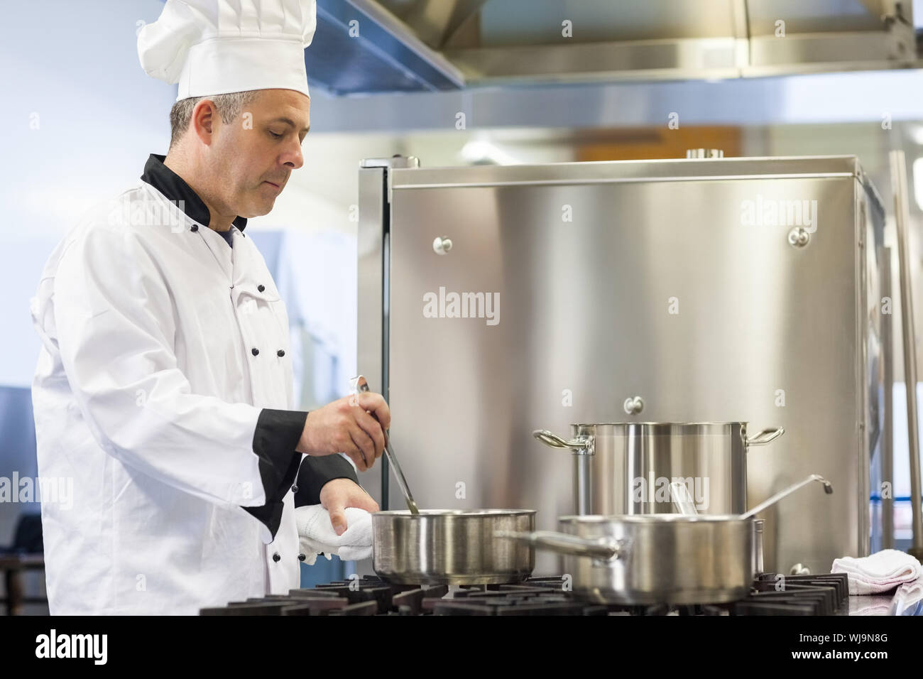 Focused head chef stirring in pot in professional kitchen Stock Photo ...