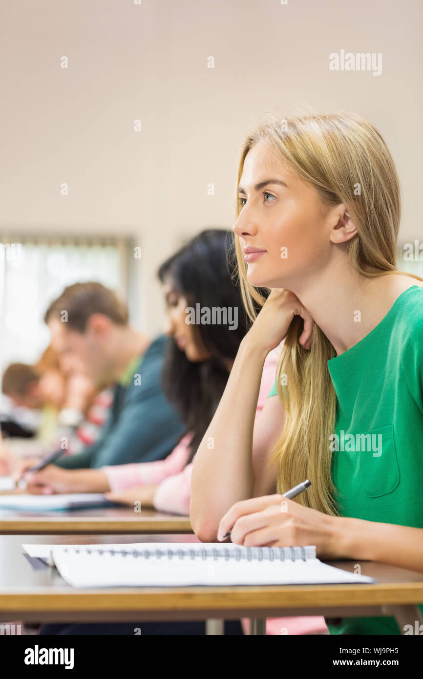 Side view of a group of young students writing notes in the classroom ...