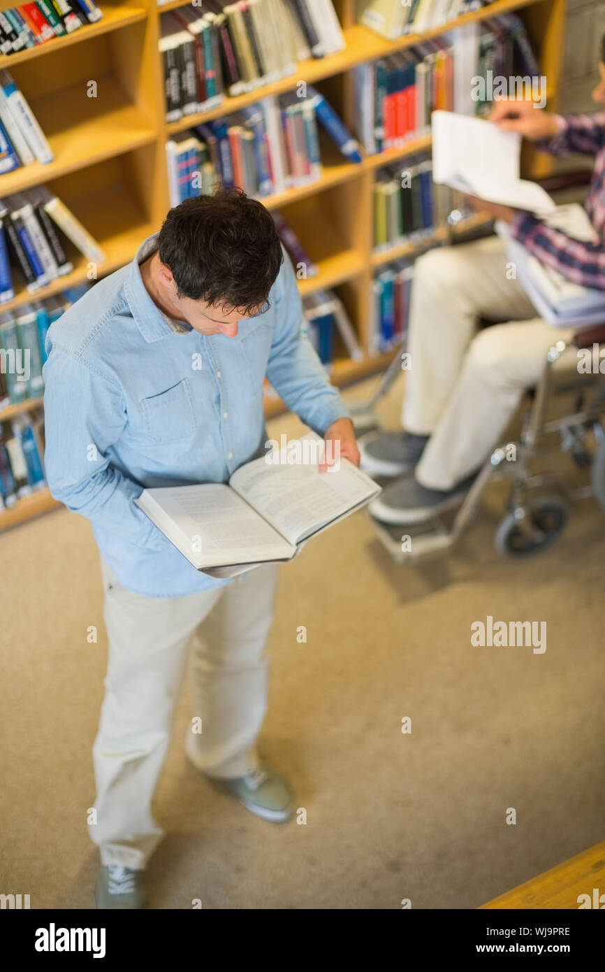 High angle view of a man and disabled student in wheelchair reading ...
