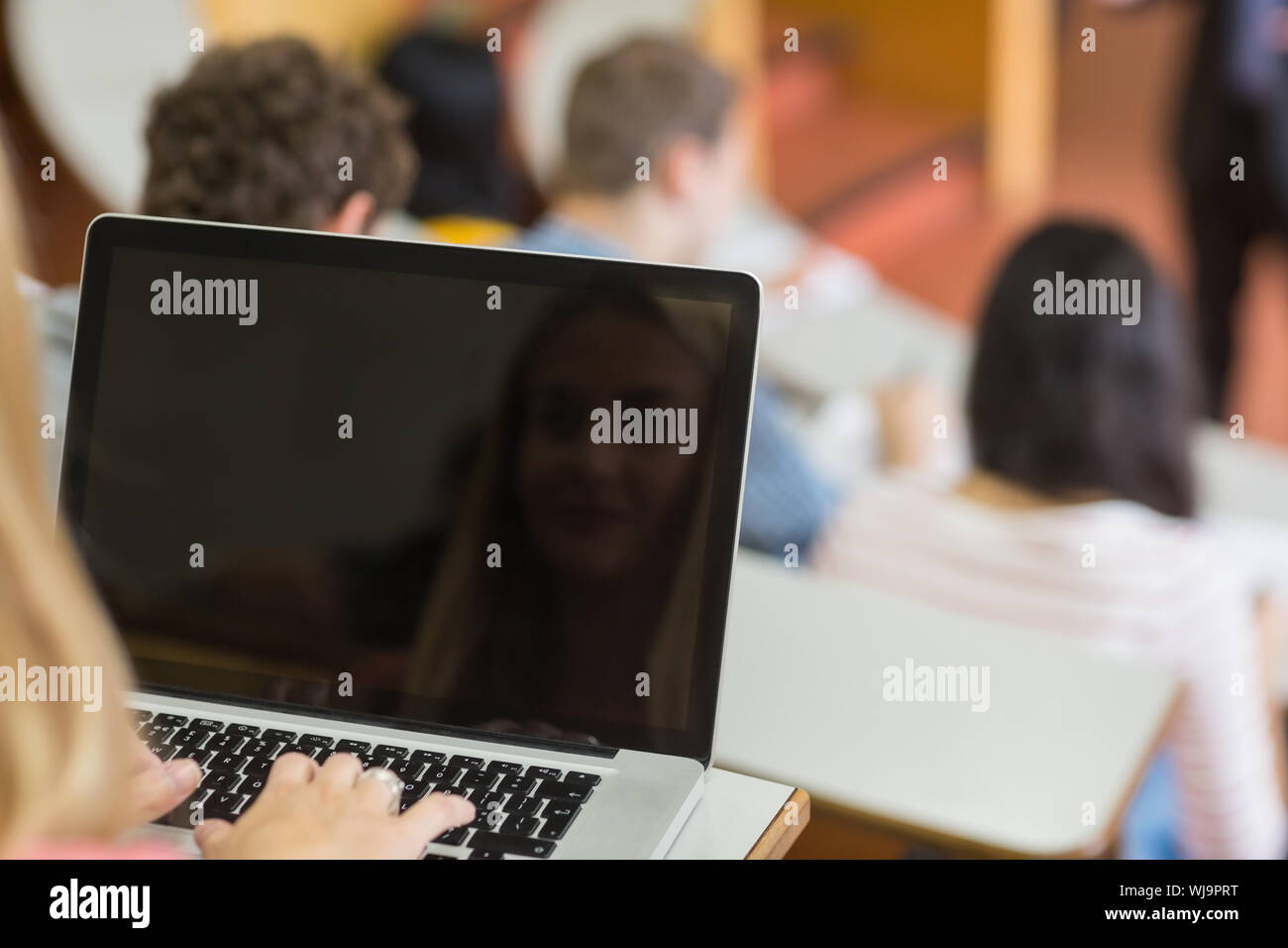 Rear view of a female using laptop with students and teacher at the ...