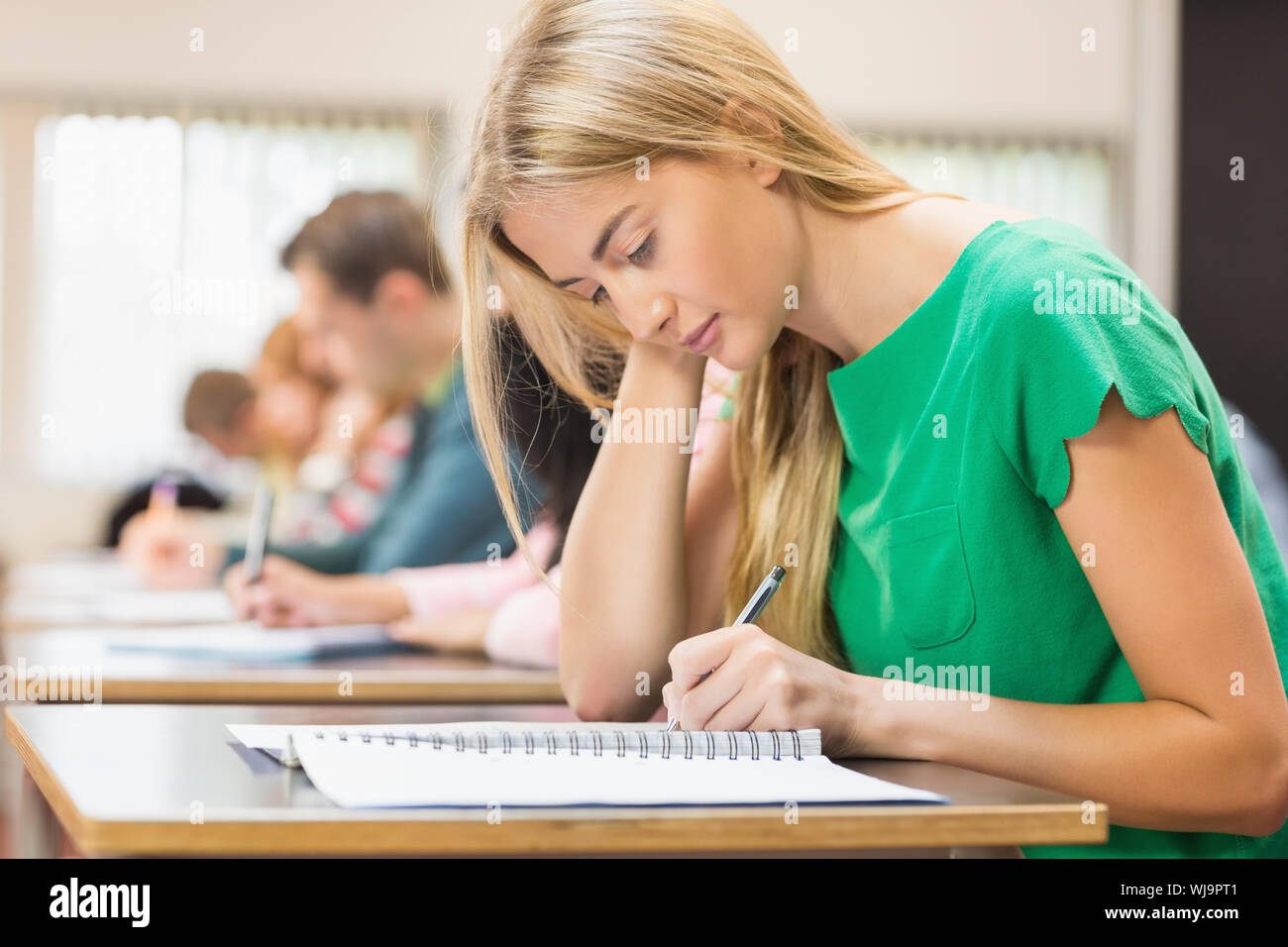 Side view of a group of young students writing notes in the classroom ...