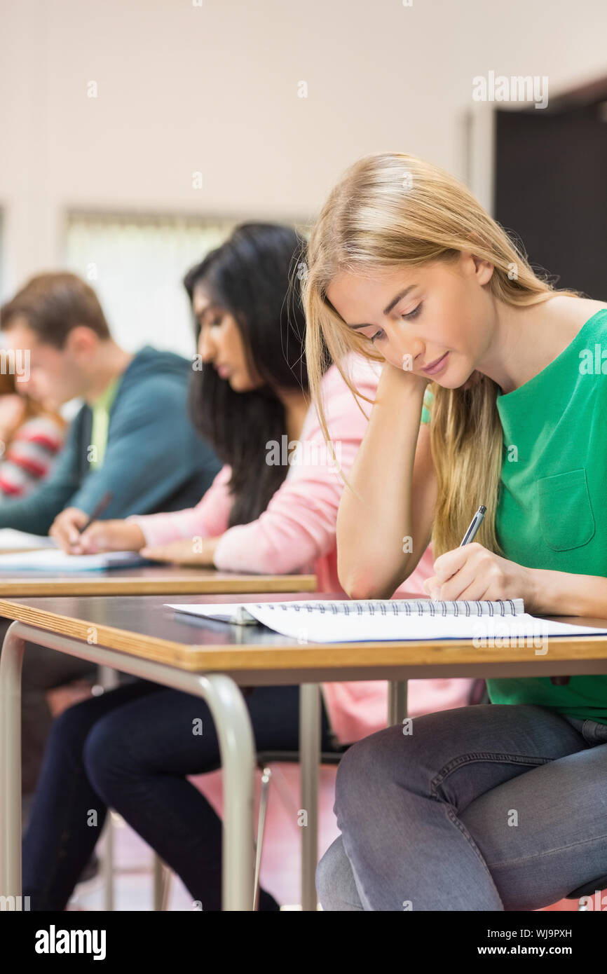Side view of a group of young students writing notes in the classroom ...
