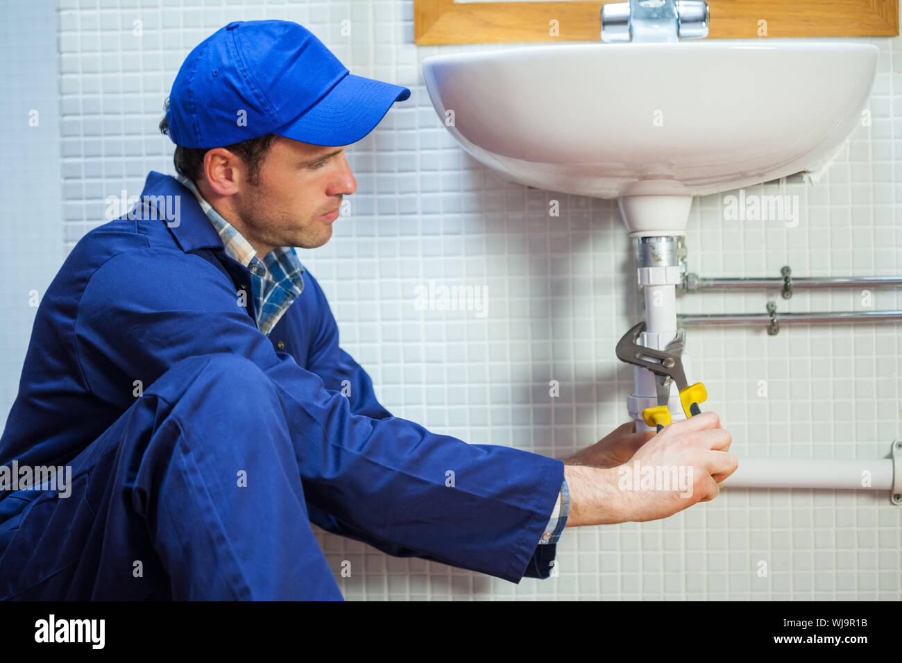 Attractive focused plumber repairing sink in public bathroom Stock ...
