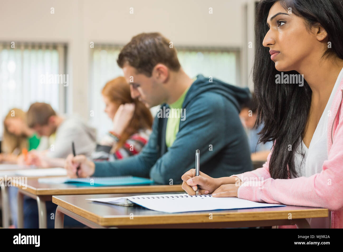 Side view of a group of young students writing notes in the classroom ...