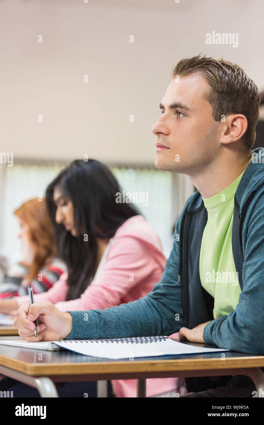Side view of a group of young students writing notes in the classroom ...