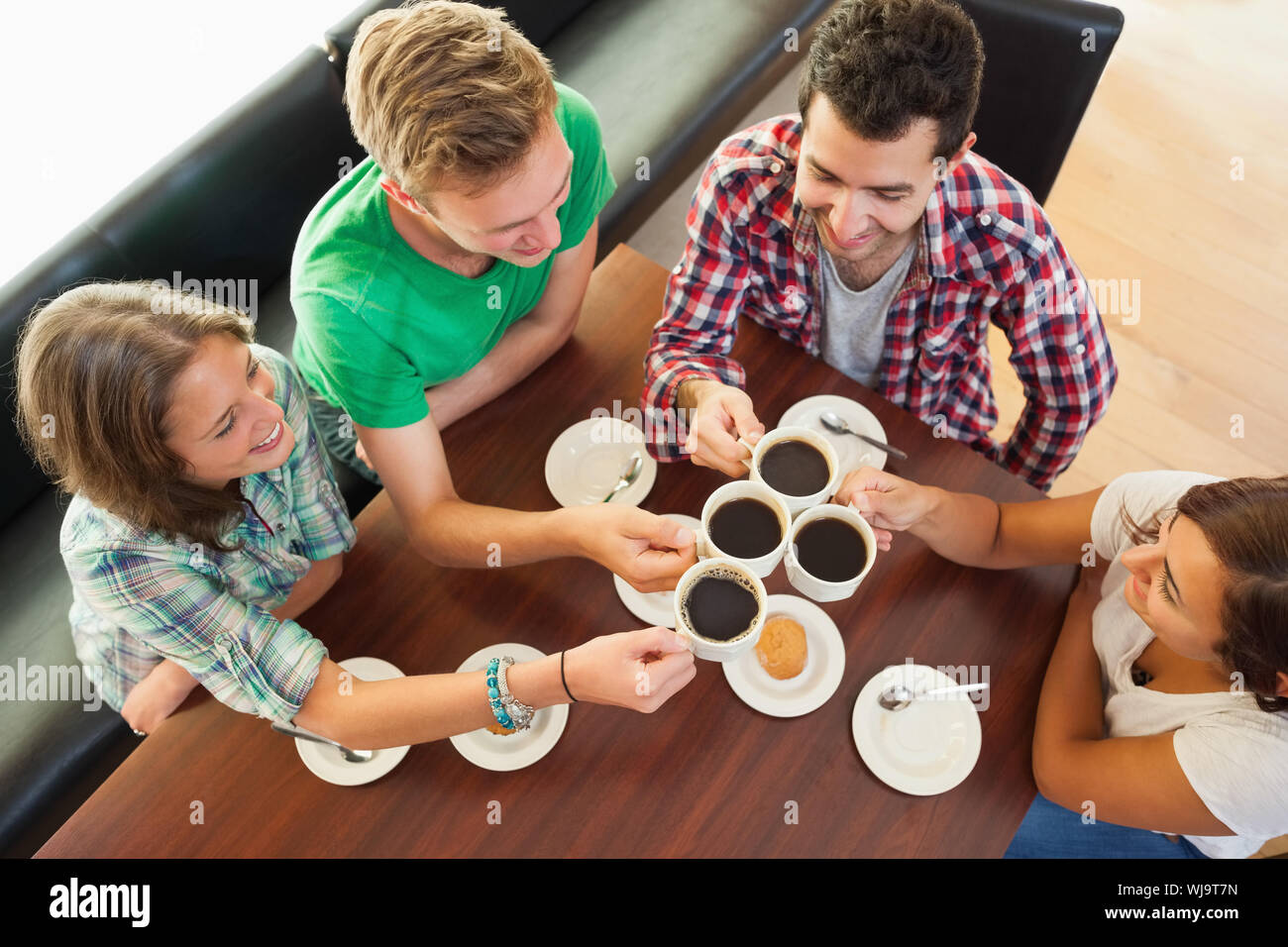Four happy students having a cup of coffee chatting in college canteen ...