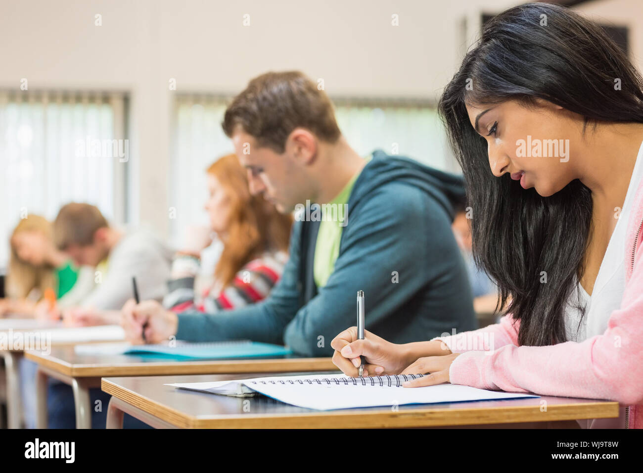 Side view of a group of young students writing notes in the classroom ...