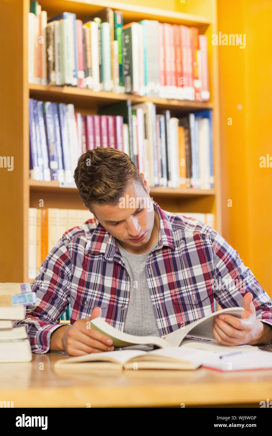 Handsome concentrating student studying his books in library Stock ...