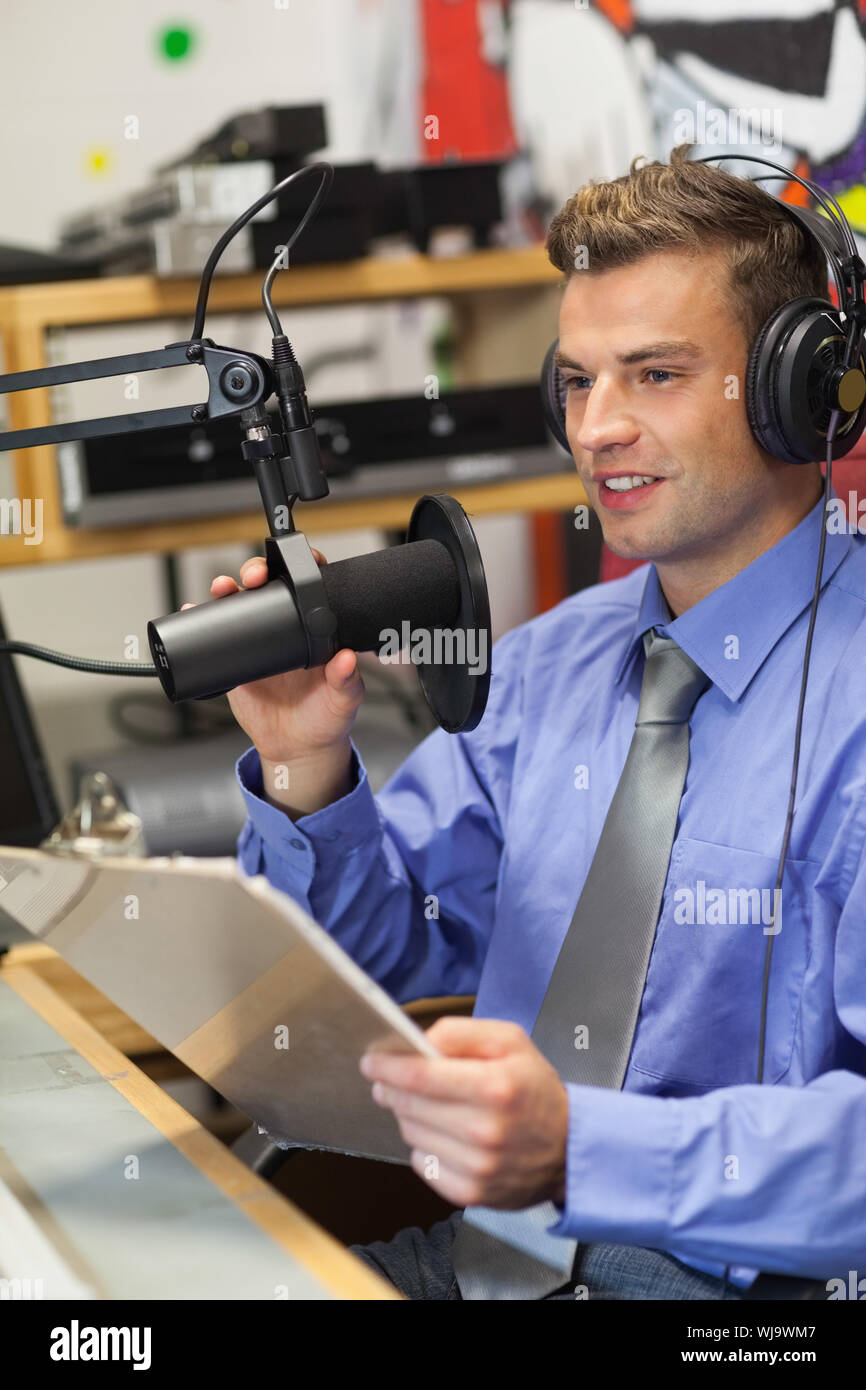 Well dressed happy radio host moderating sitting in studio at college ...