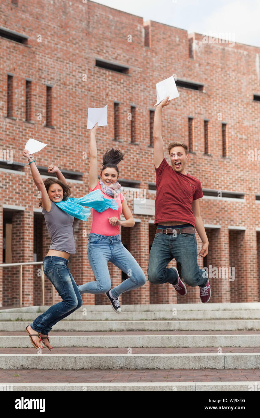 Happy students jumping in the air holding exam in school Stock Photo ...
