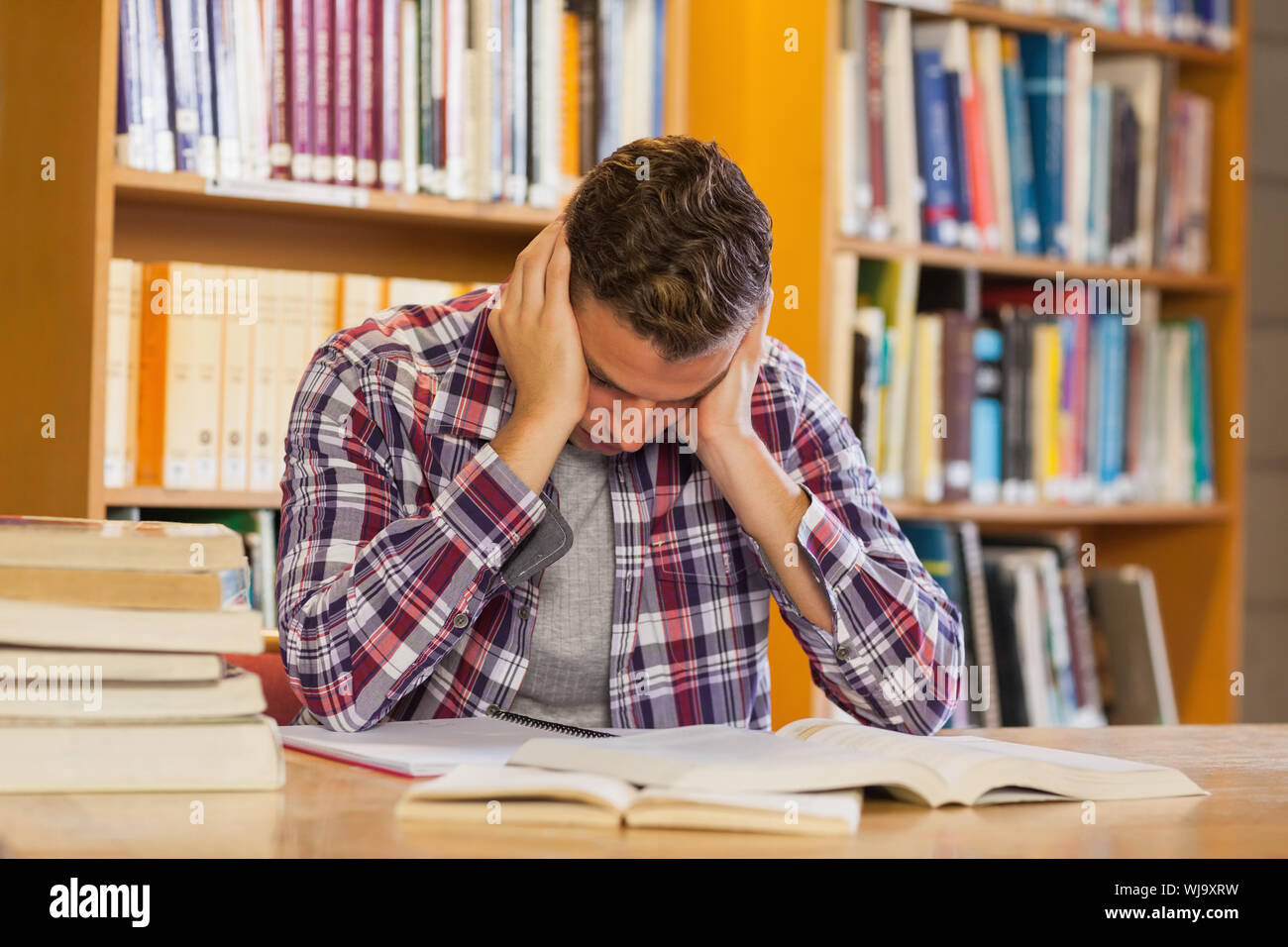 Handsome frustrated student studying his books in library Stock Photo ...