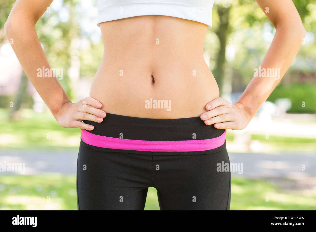 Mid section picture of toned belly from a woman in a park on a sunny ...