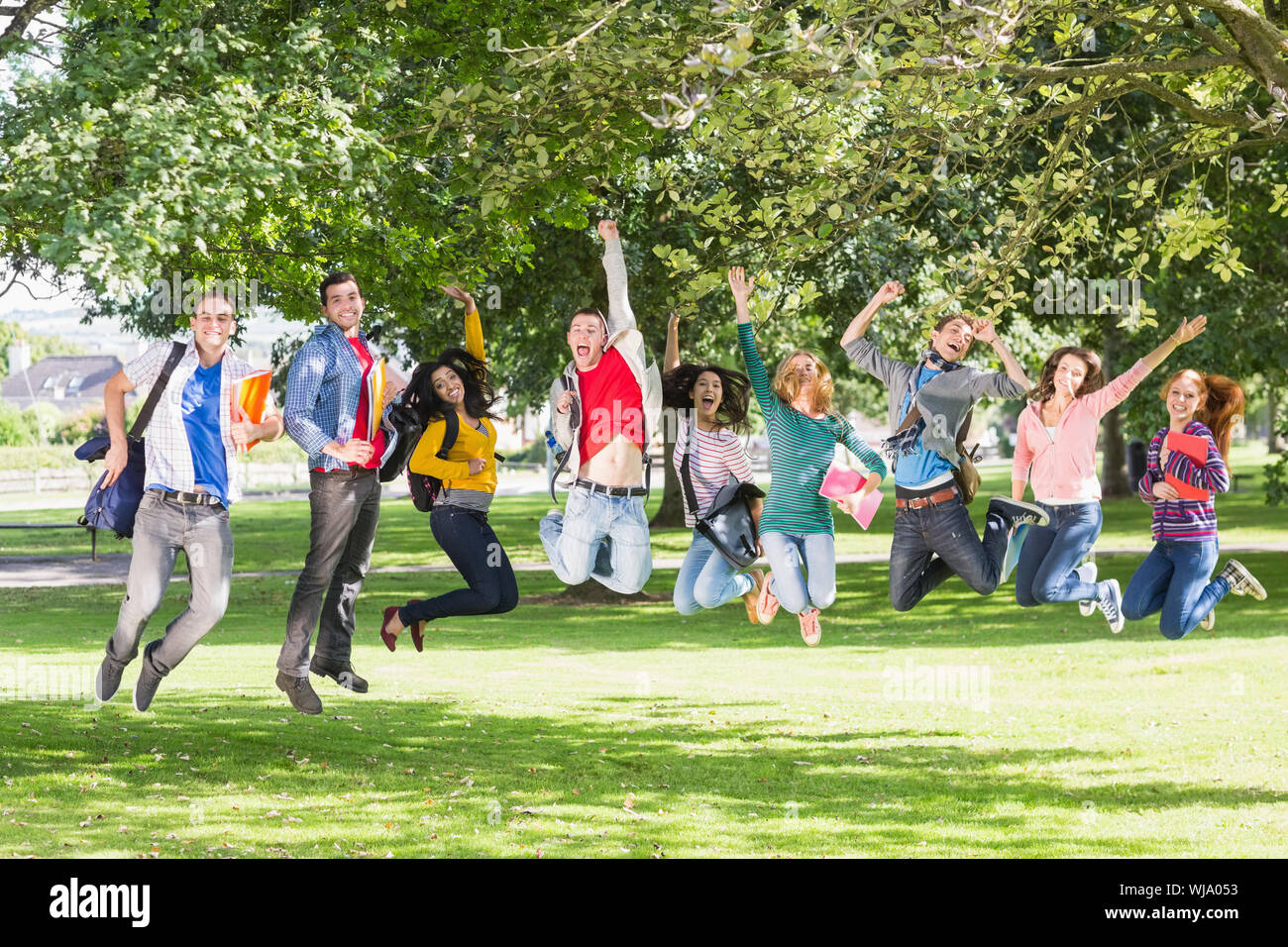 Full length of a group of college students jumping in the park Stock ...