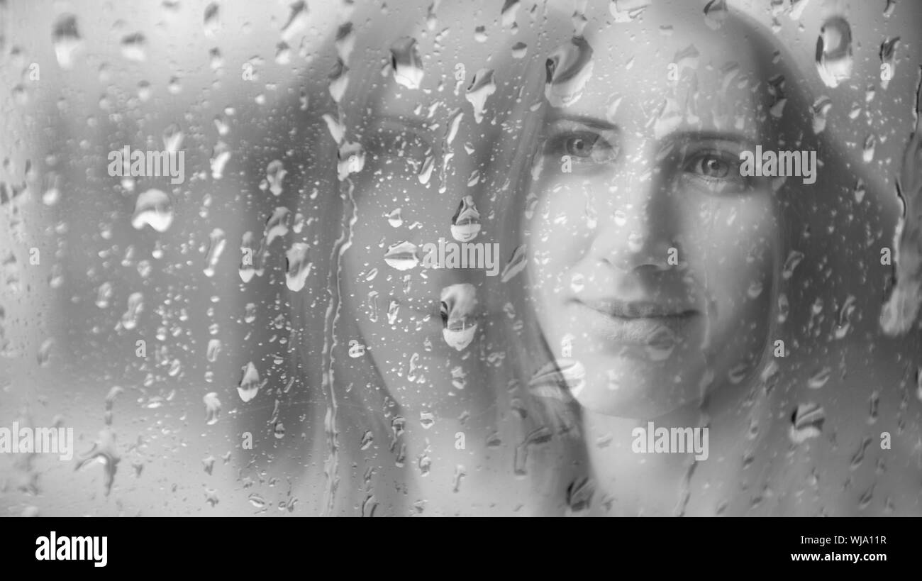 Woman looking through window rain Black and White Stock Photos & Images ...