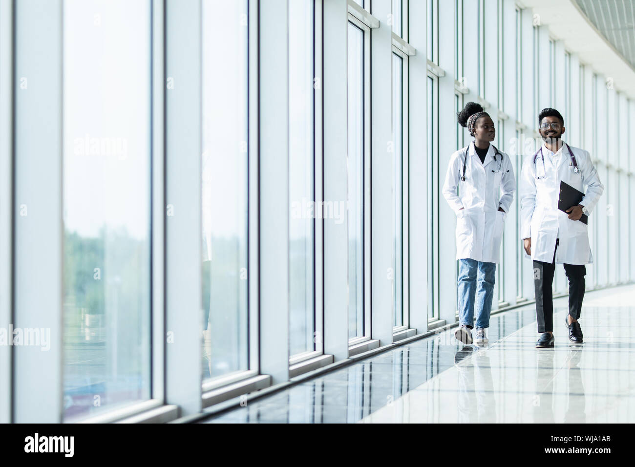 Two doctors discussing diagnosis while walking Stock Photo - Alamy