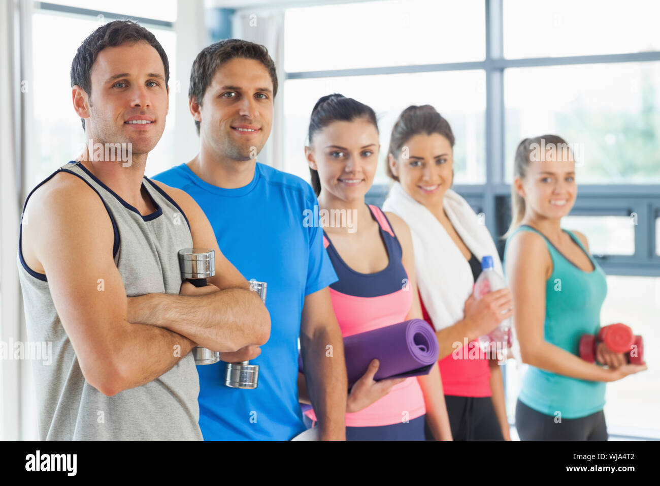 Portrait of a group of fitness class standing in row at a bright ...