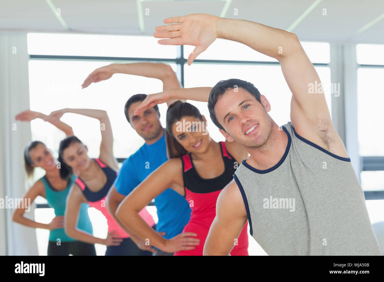 Portrait of sporty people doing power fitness exercise in row at yoga ...