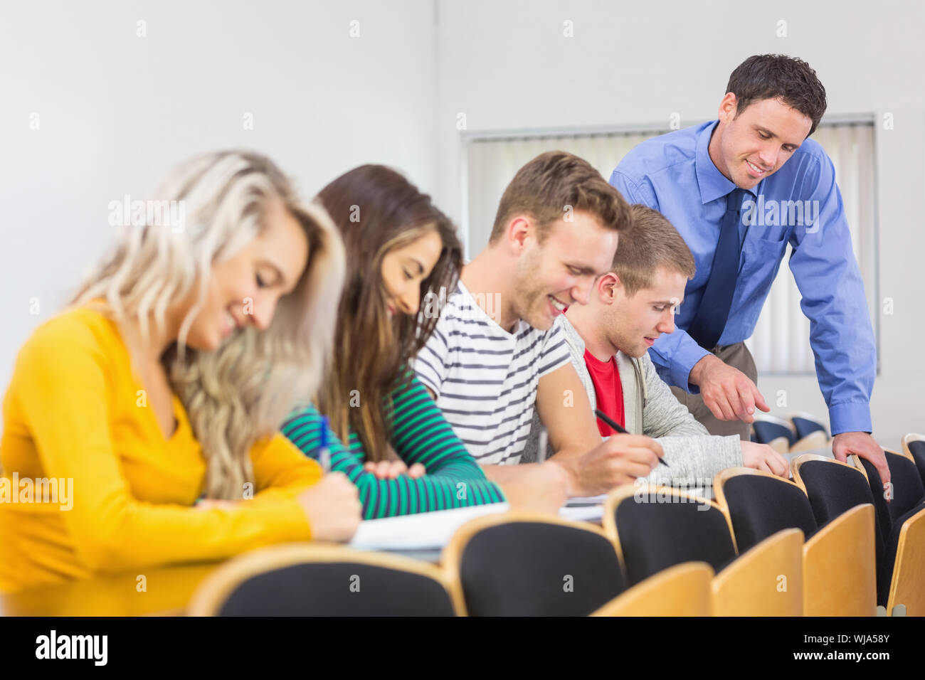 Side view of teacher with college students in row at the classroom ...
