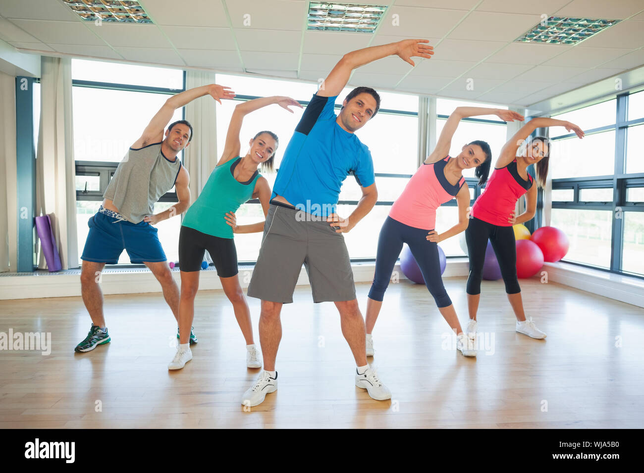Full length portrait of smiling people doing power fitness exercise at ...