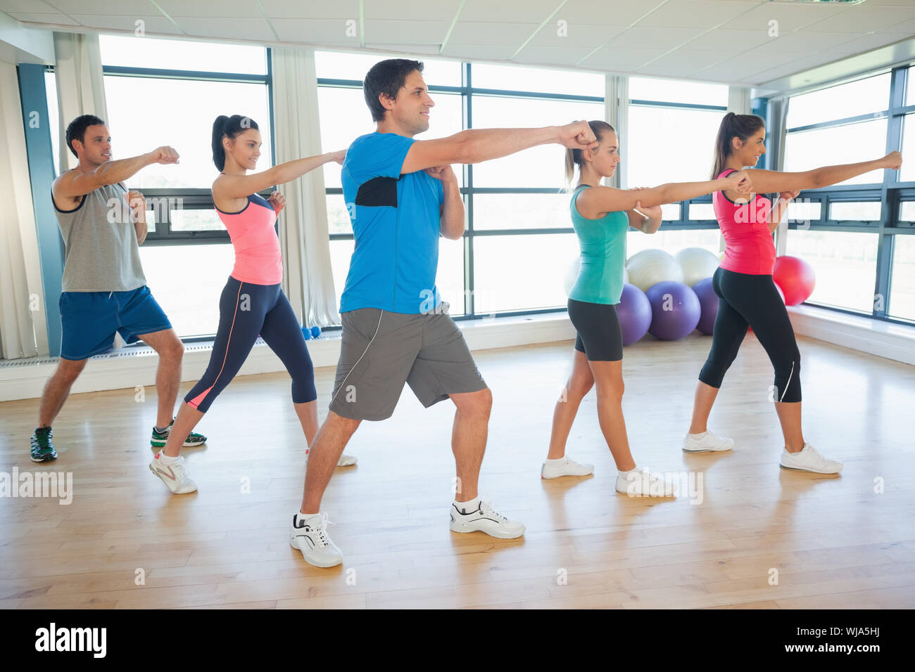 Full length of sporty people doing power fitness exercise at yoga class ...