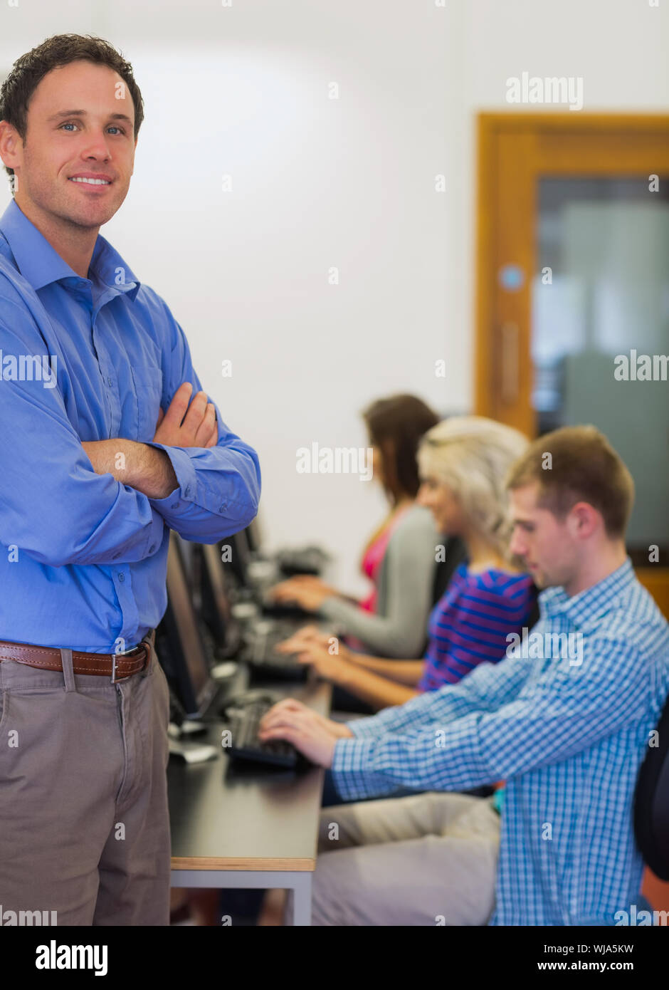 Portrait of a smiling teacher with young college students using ...