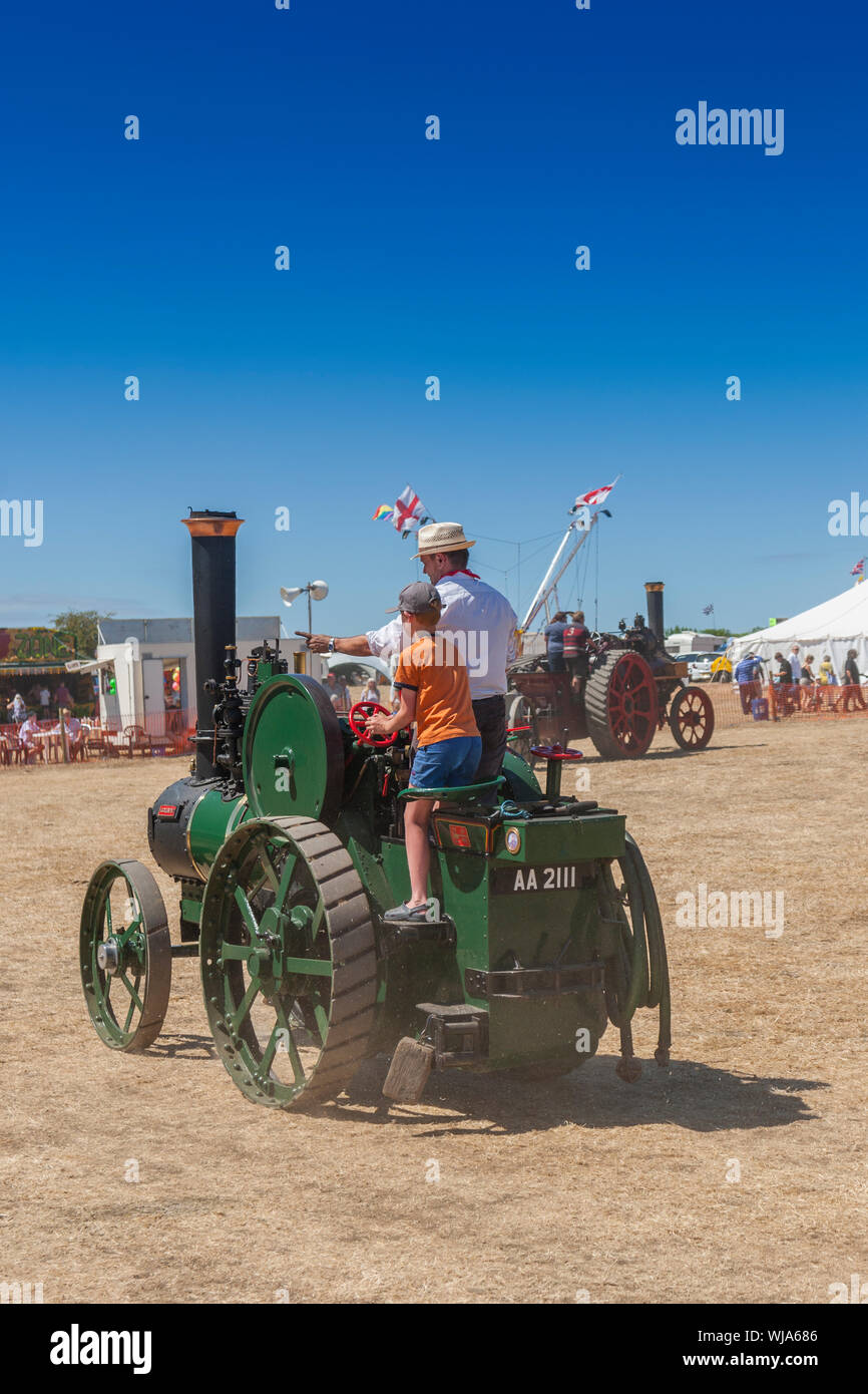 A minature Wallis traction engine at speed with father and son at the ...