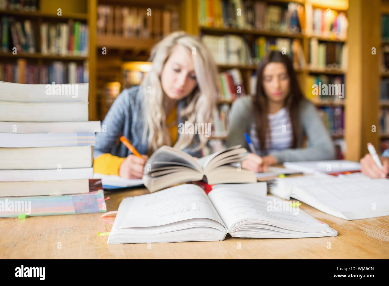 Two blurred students writing notes at desk in the college library Stock ...