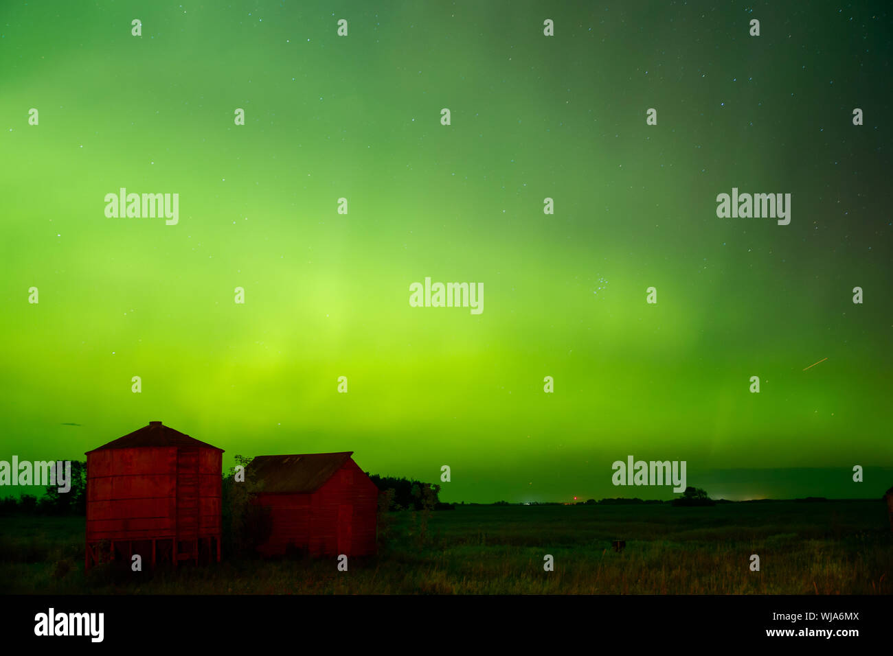 Bright green northern lights over red agricultural sheds in a canadian ...