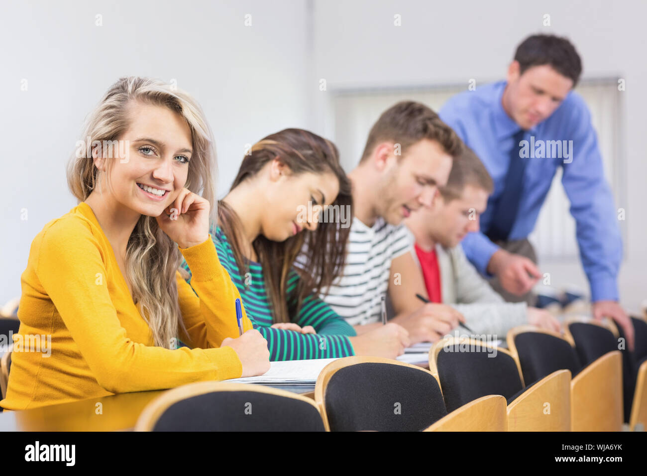 Side view of teacher with college students in row at the classroom ...