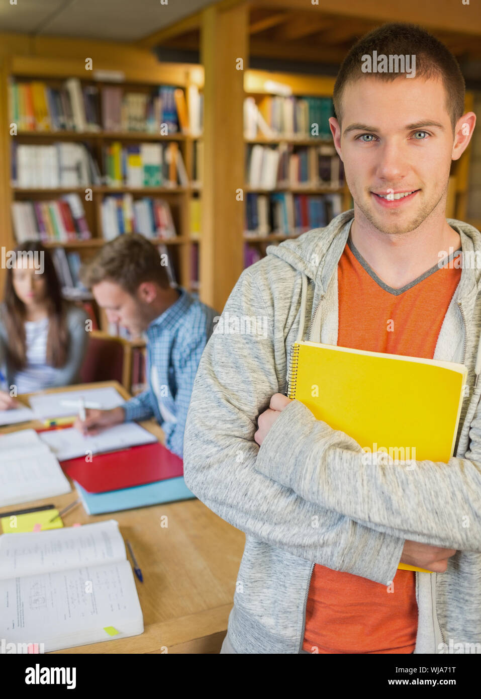 Portrait of a smiling male student with others in background in the ...