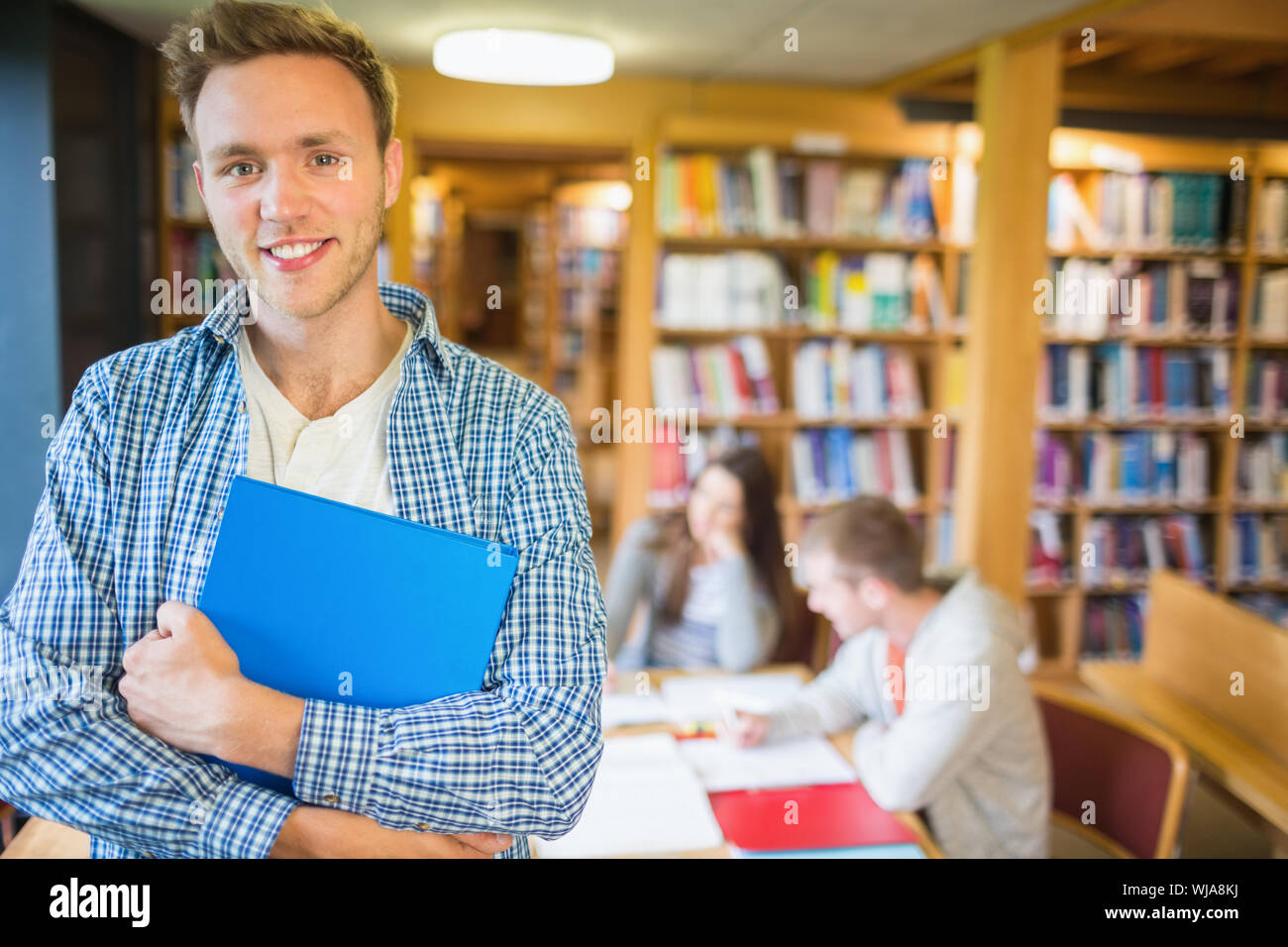 Portrait of a smiling male student with others in background in the ...