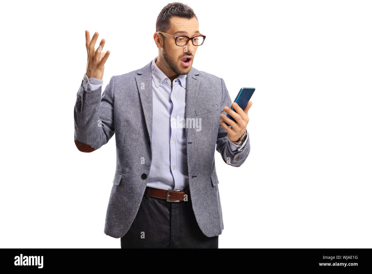 Confused young man looking at his mobile phone and gesturing with hand ...