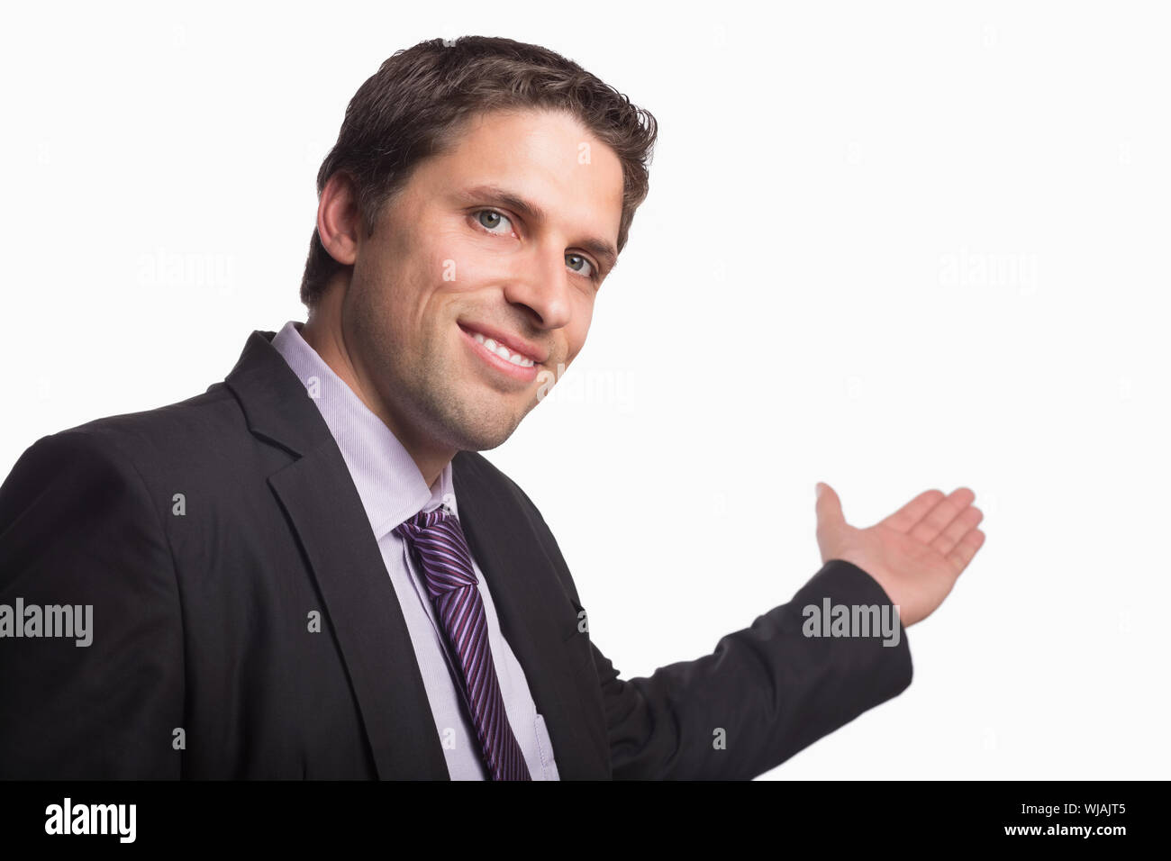 Businessman giving a welcome gesture against white background Stock ...