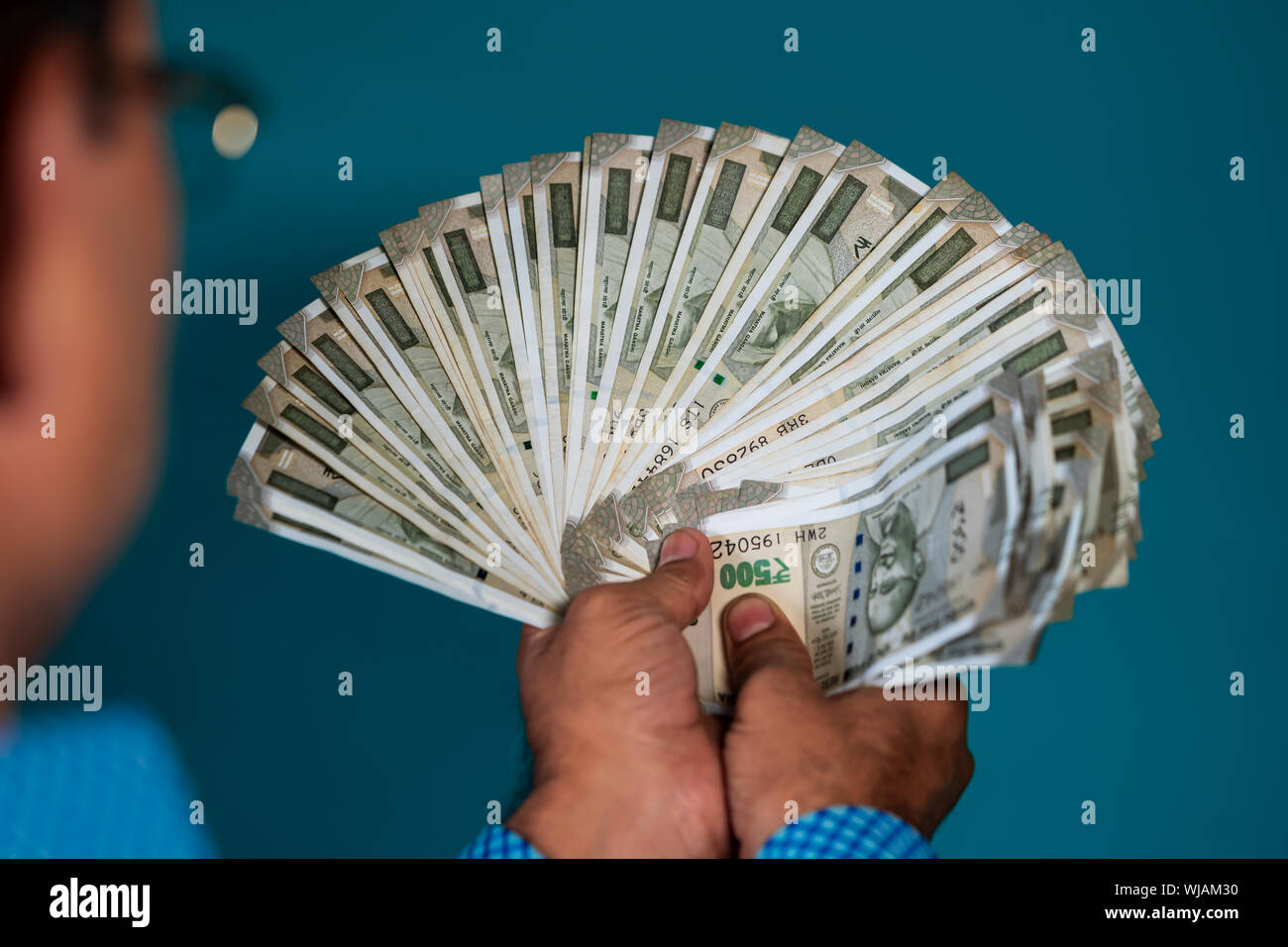 Indian male hand holding won lottery money spread apart in fan shape ...