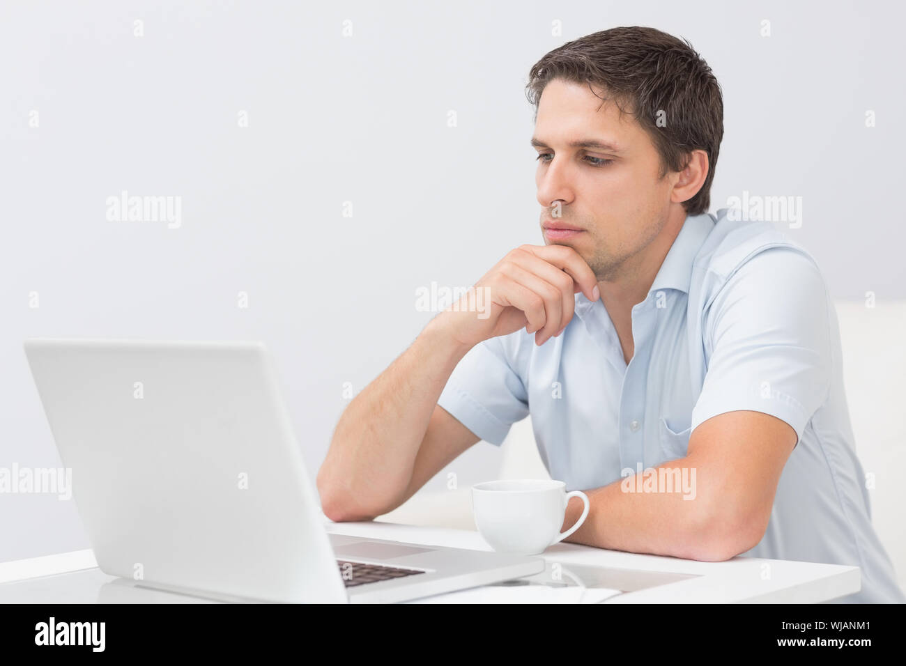 Serious young man using laptop at home Stock Photo - Alamy