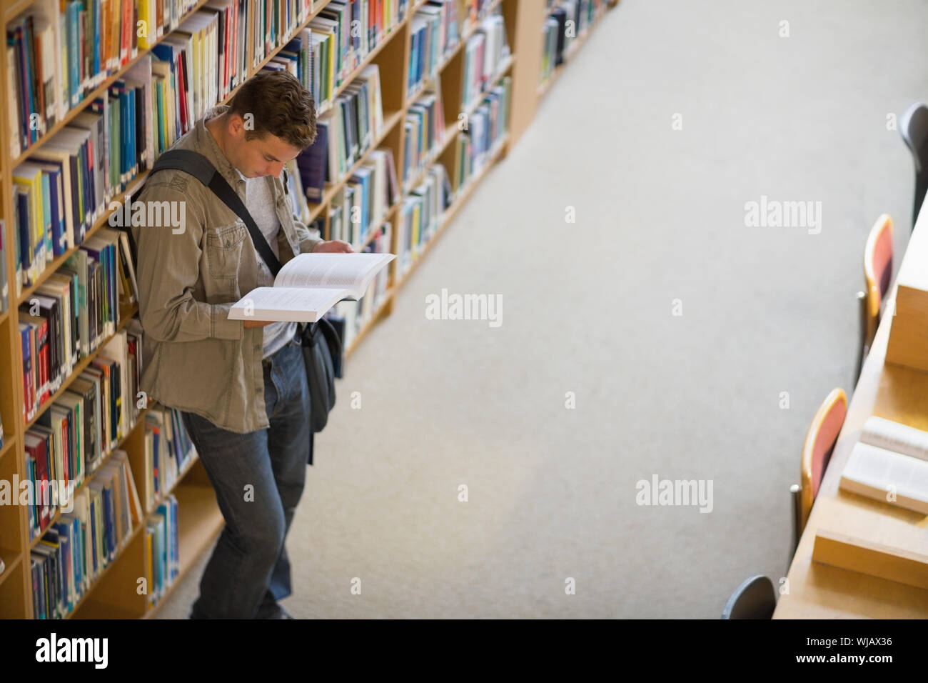 Student reading a book from shelf standing in library Stock Photo - Alamy