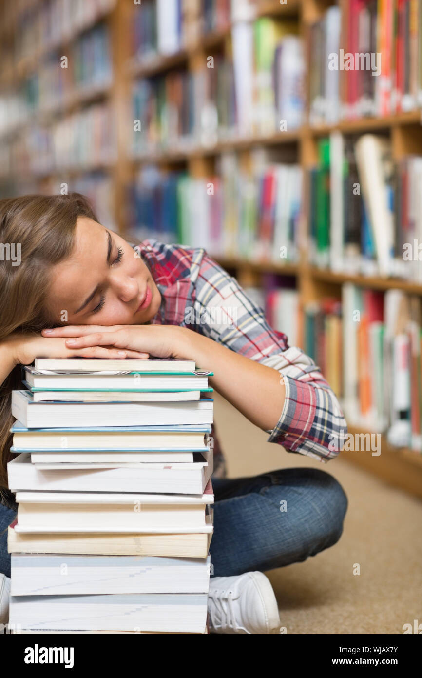 Napping student sitting on library floor leaning on pile of books Stock ...