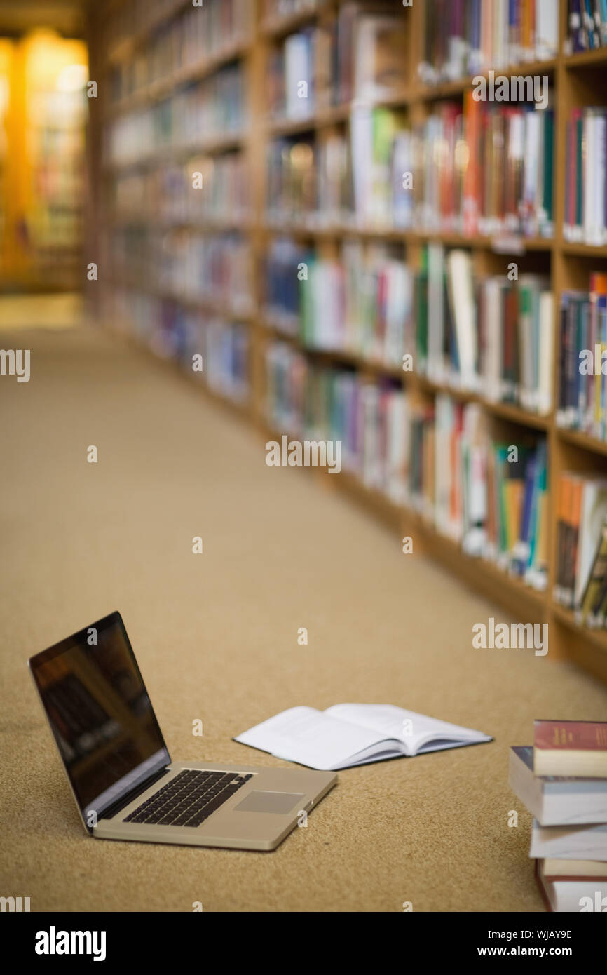 Laptop and books on the floor of library Stock Photo - Alamy