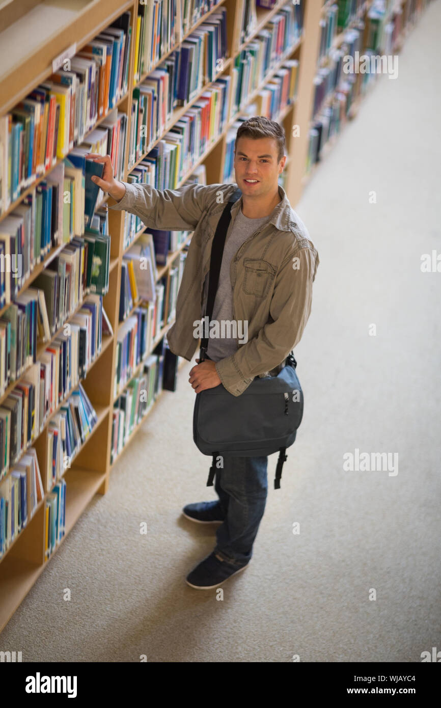 Student taking a book from shelf in library smiling at camera Stock ...