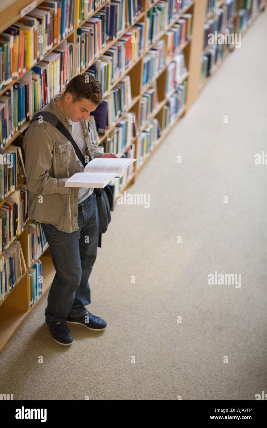 Student reading a book standing in library Stock Photo - Alamy