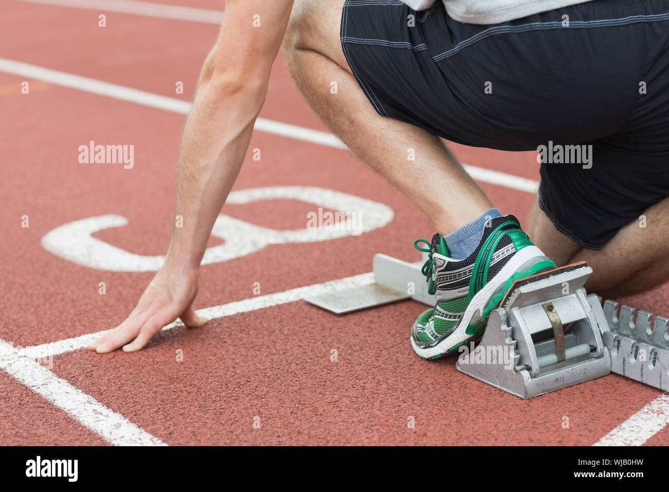 Mid section of a man ready to race on running track Stock Photo - Alamy