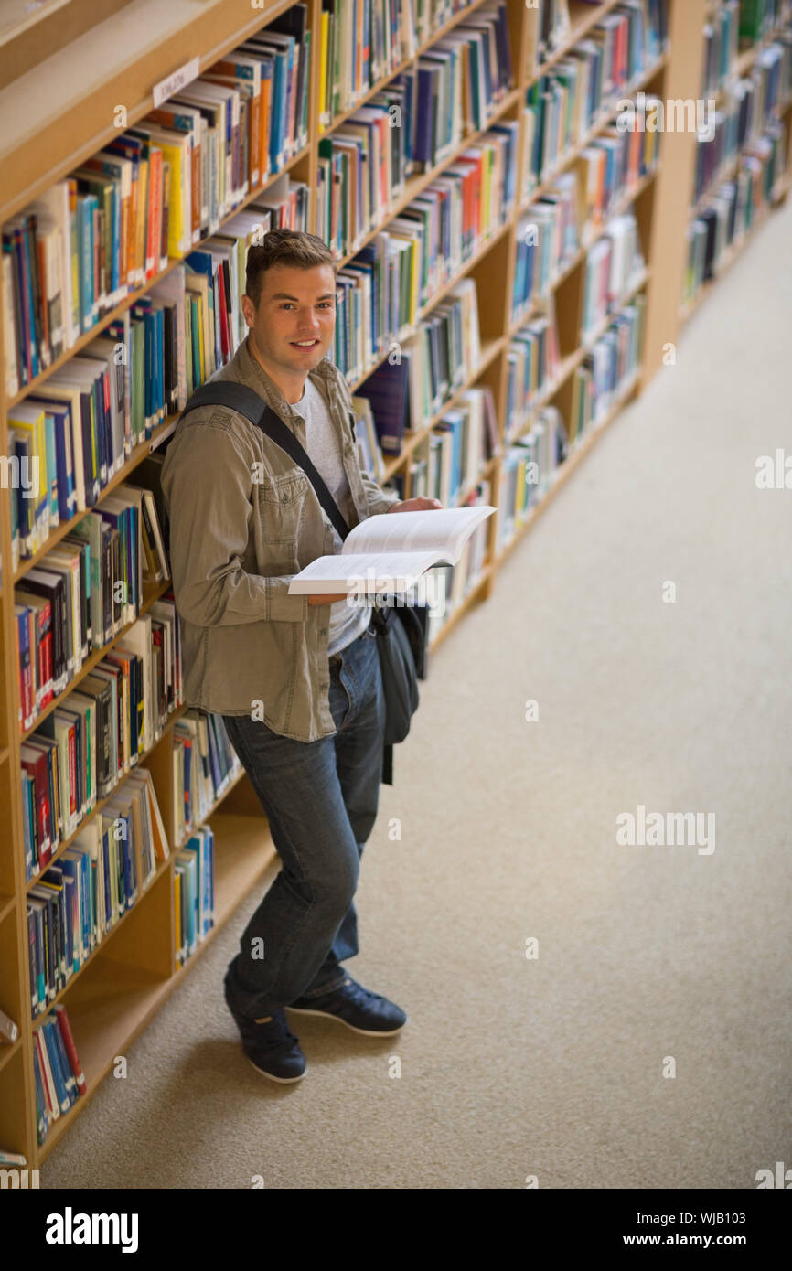 Student reading a book standing in library smiling at camera Stock ...
