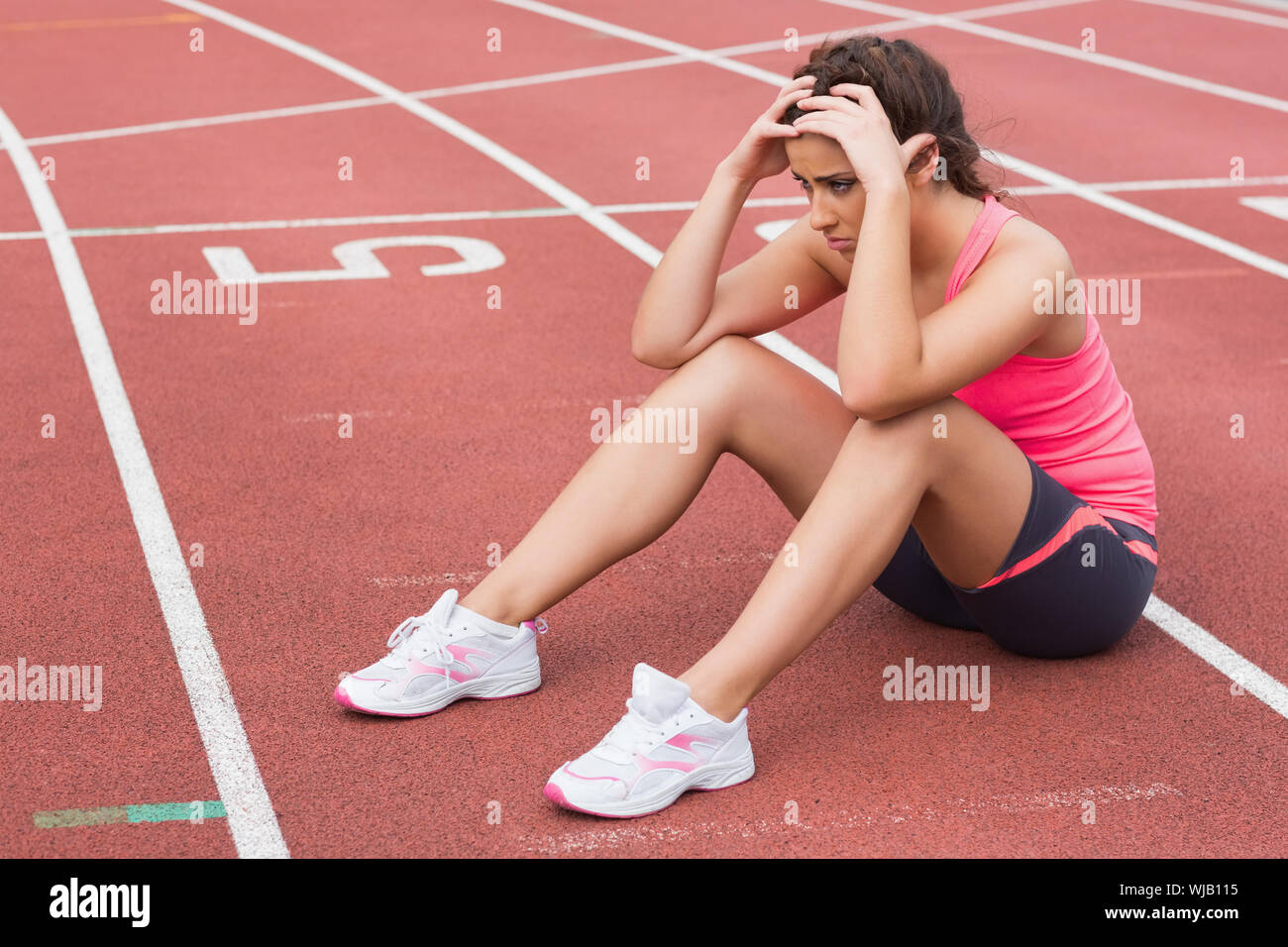 Young sporty woman sitting on the running track Stock Photo - Alamy