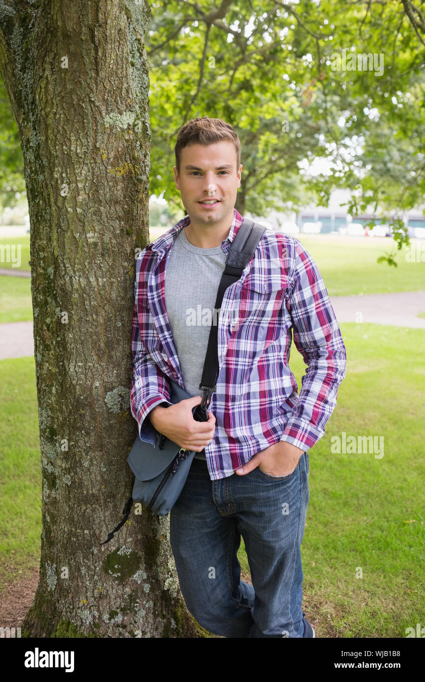 Happy student leaning on tree holding her books Stock Photo - Alamy