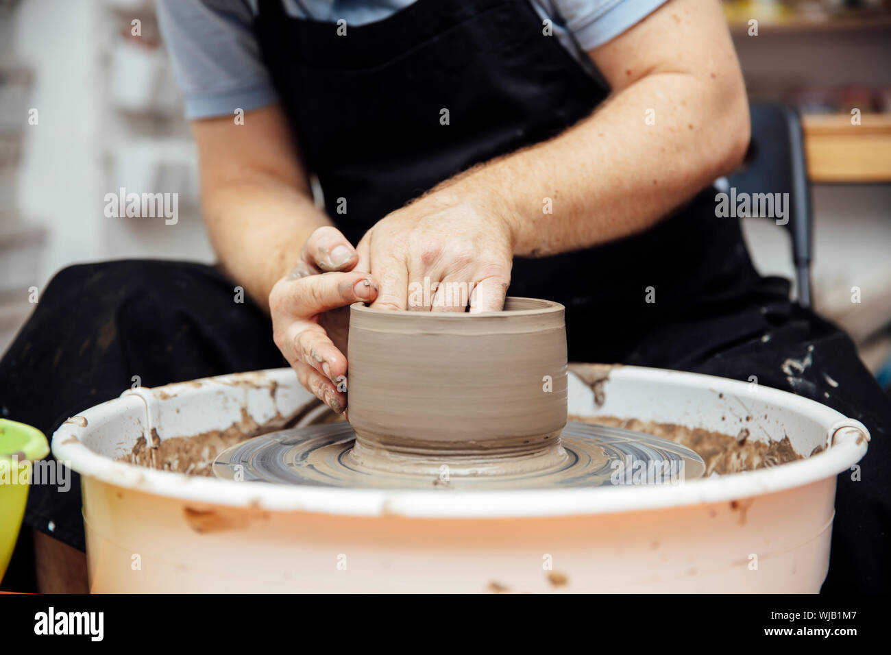 Close up detail view at an mail artist makes clay pottery on a spin ...