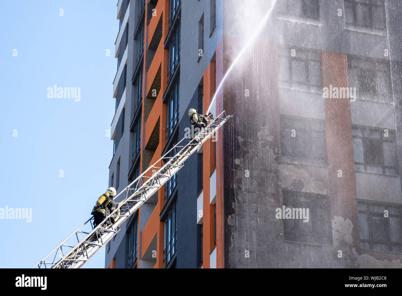 fireman climbing a ladder with water hose for extinguish fire ...